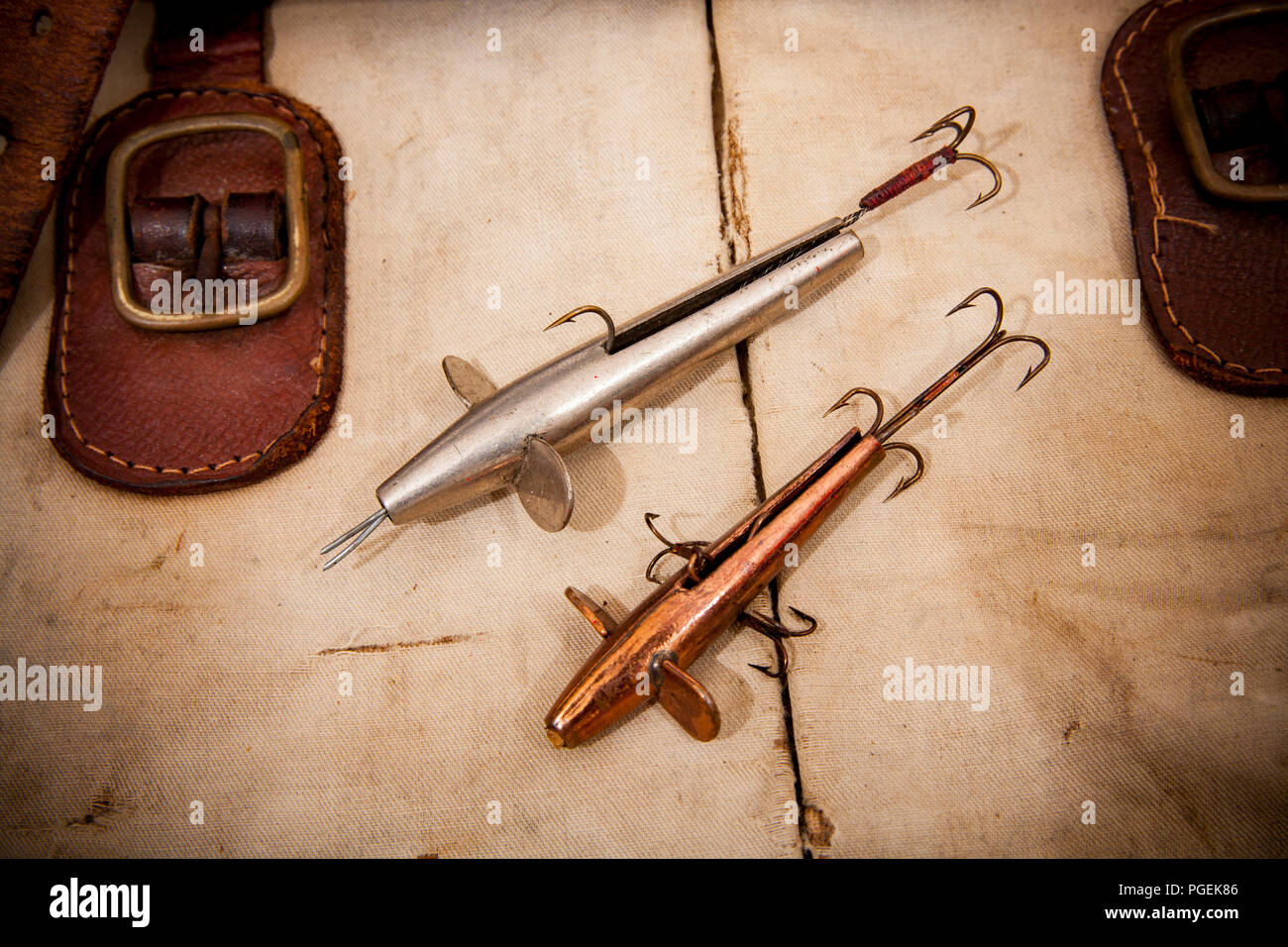 Two old metal Devon minnow lures with hooks displayed on an old fishing ...