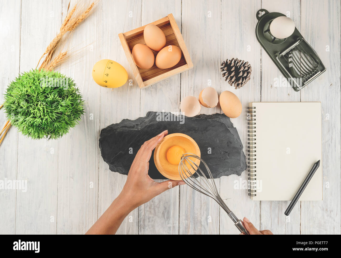 Top view of woman chef breaking an egg into the wood bowl. Female chef ...