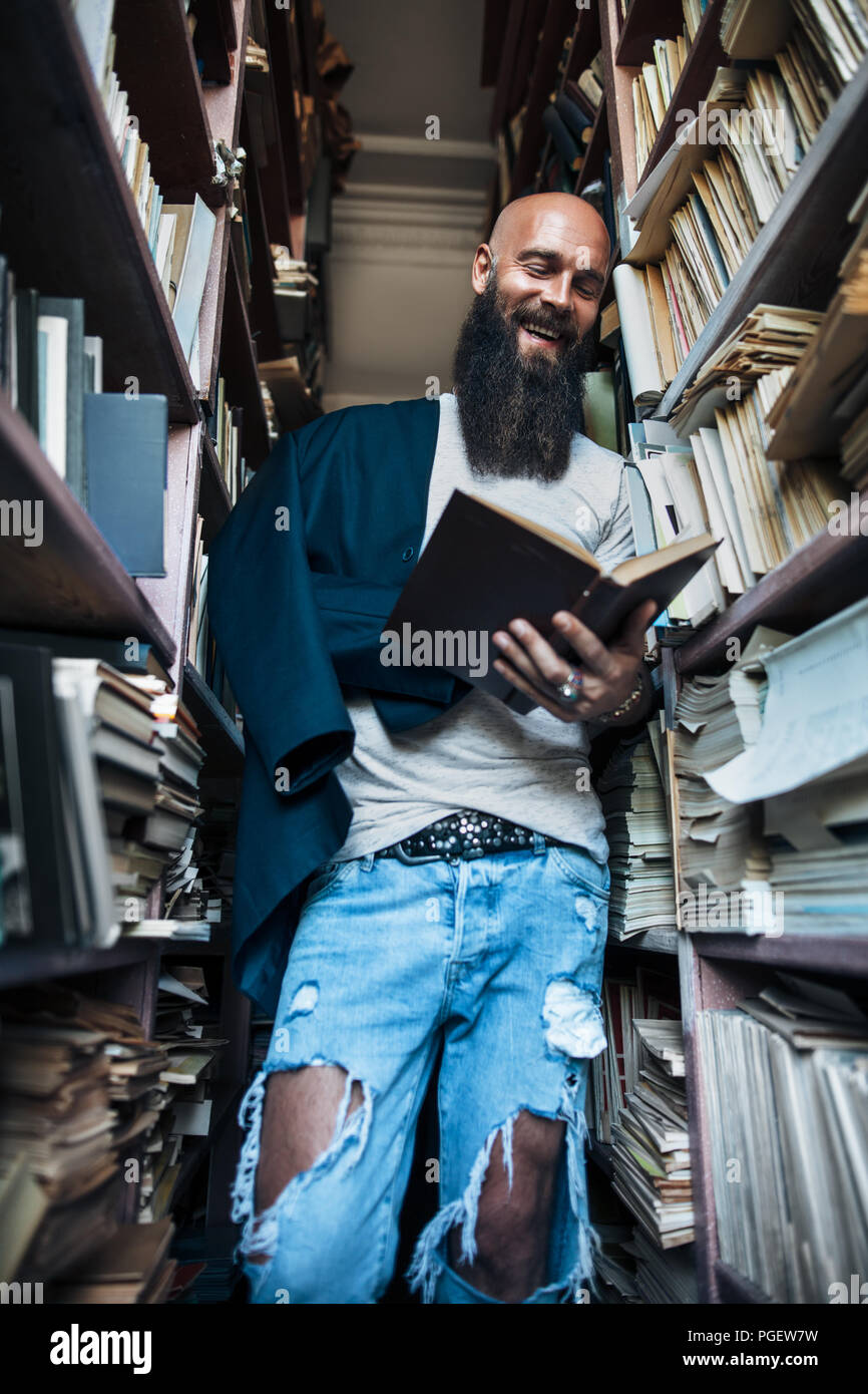Happy smiling man reading book in bookshelves background. education ...