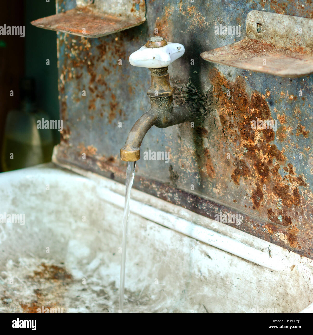 Water flows from a retro plumbing tap into an old sink. Vintage ...