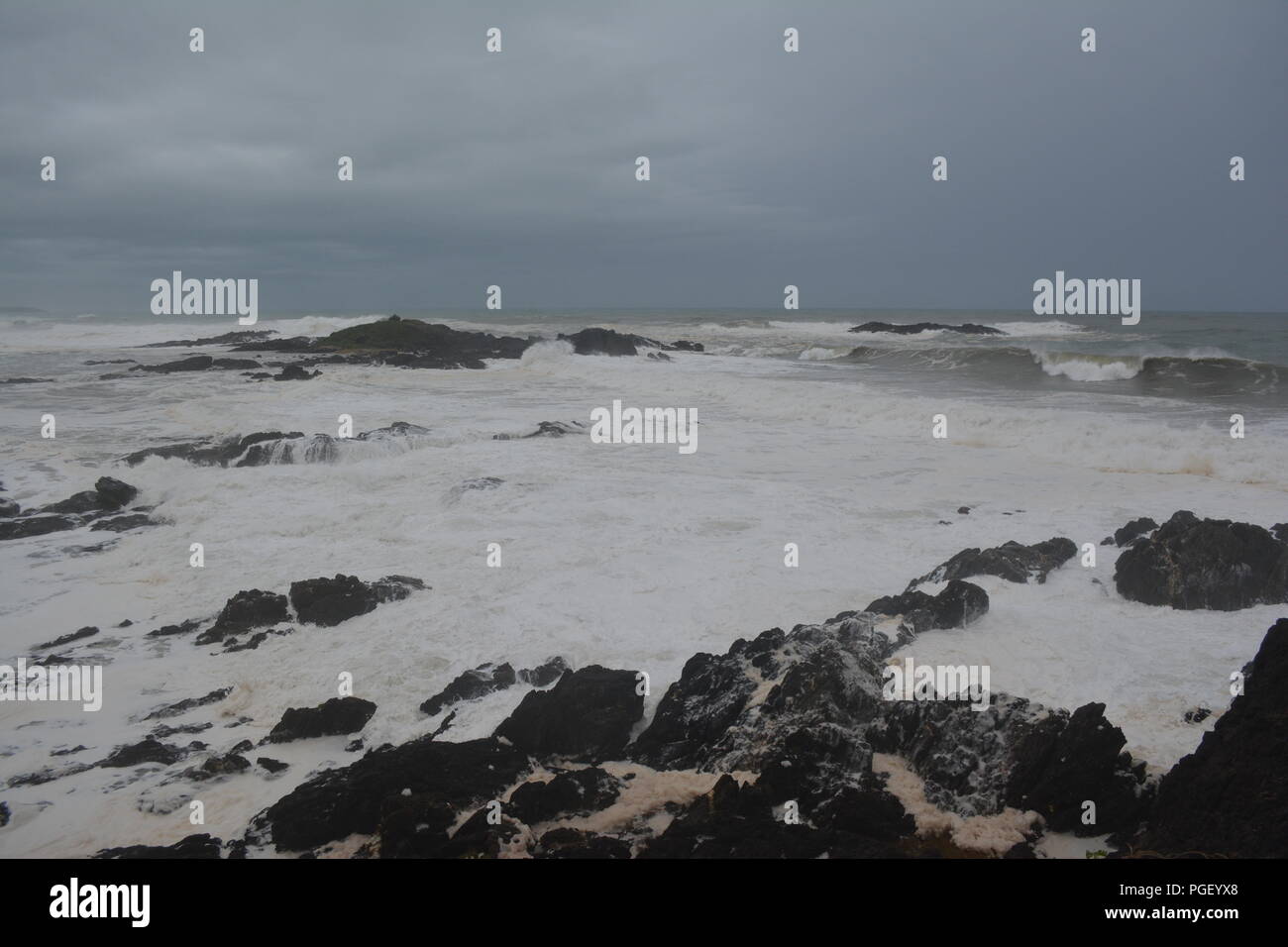 Foamy Sawtell beach in Winter, choppy seas, waves crashing over rocks ...