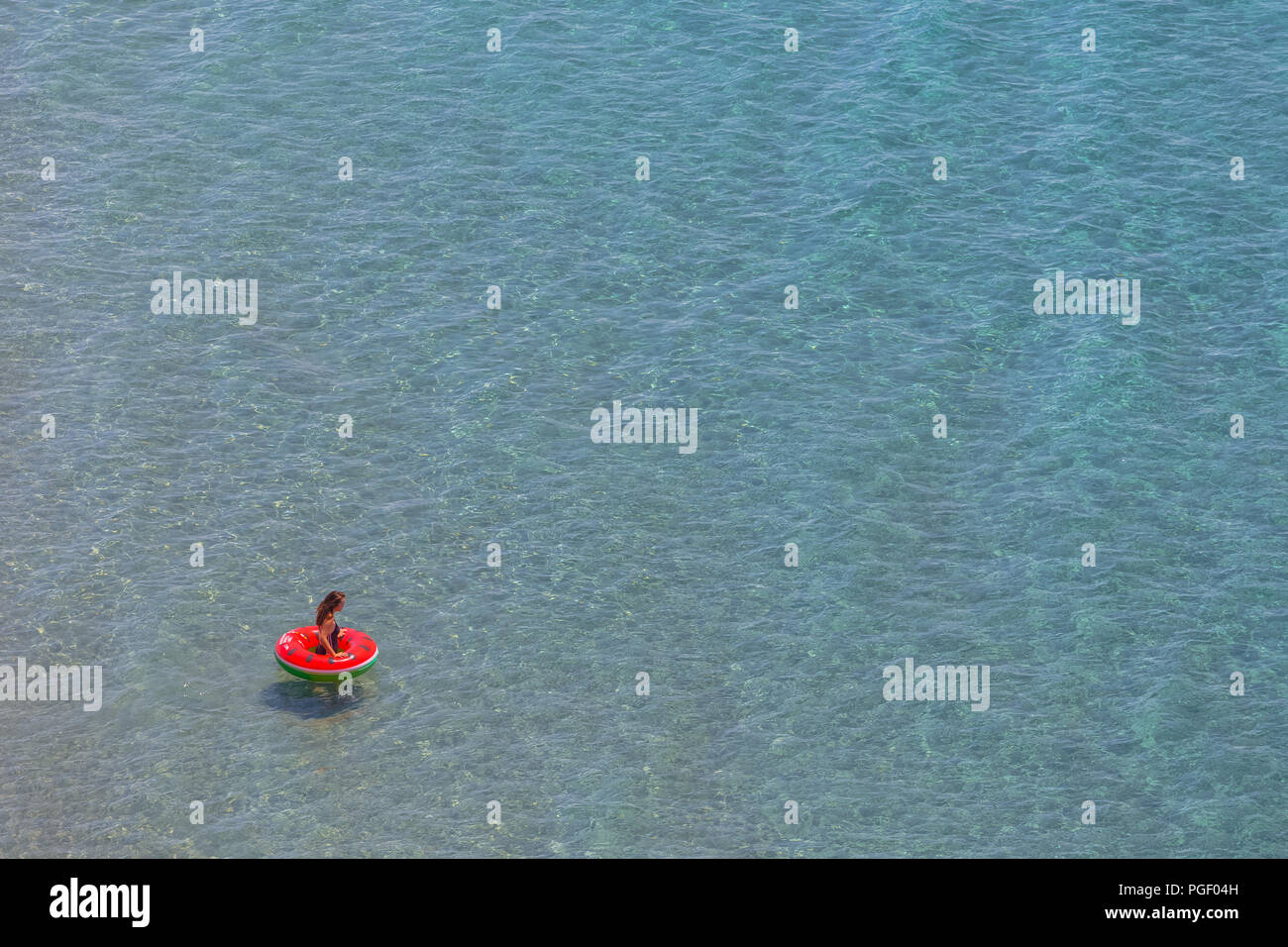 Beautiful girl having fun in a red melon shaped buoy floating onto the ...