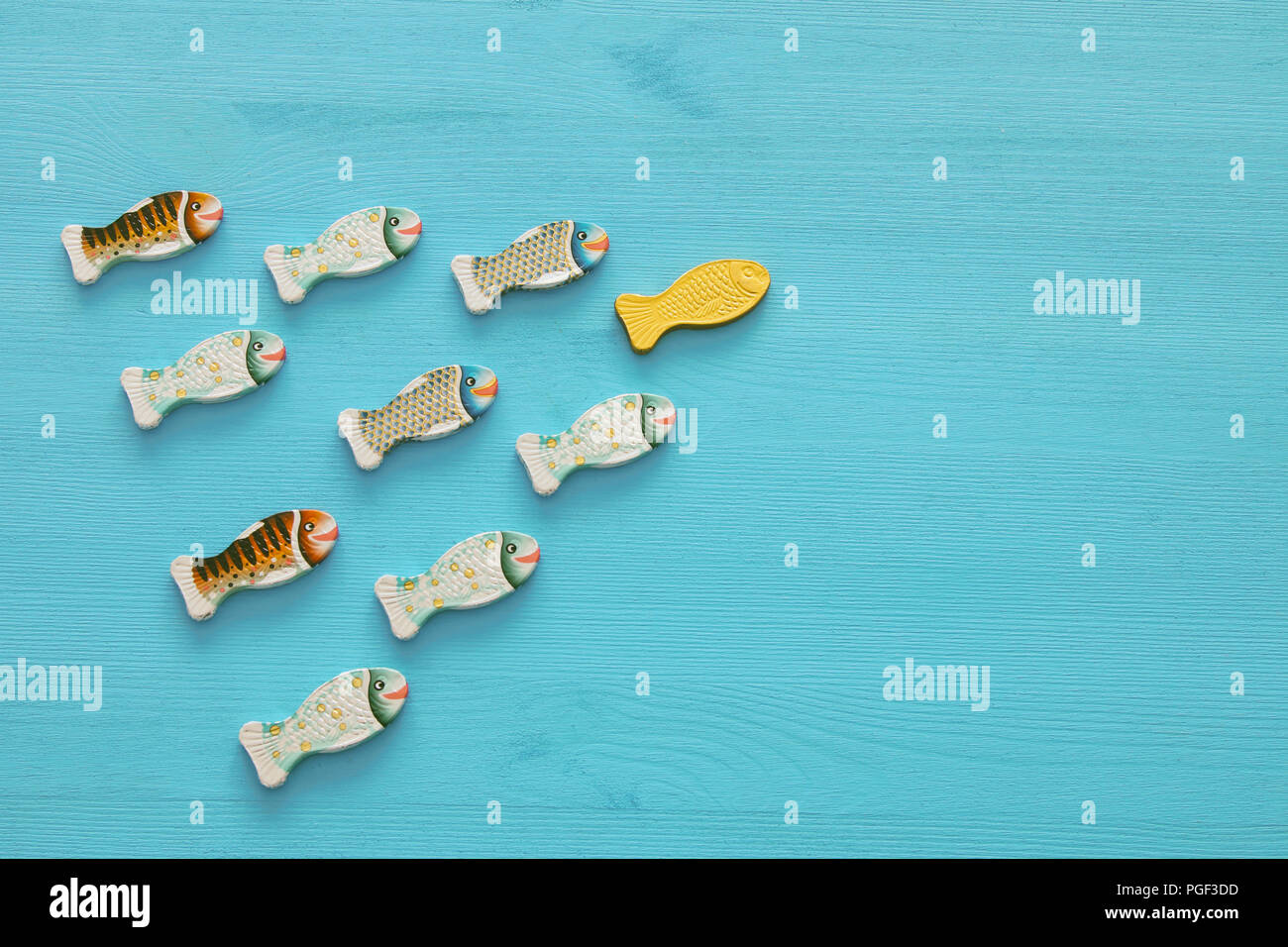 Leadership concept with swimming fish on wooden background. One leader ...