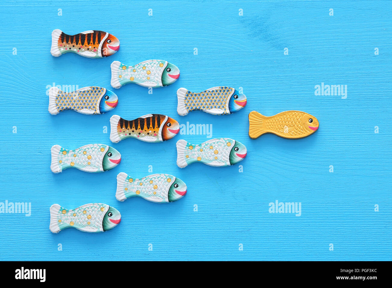 Leadership concept with swimming fish on wooden background. One leader ...