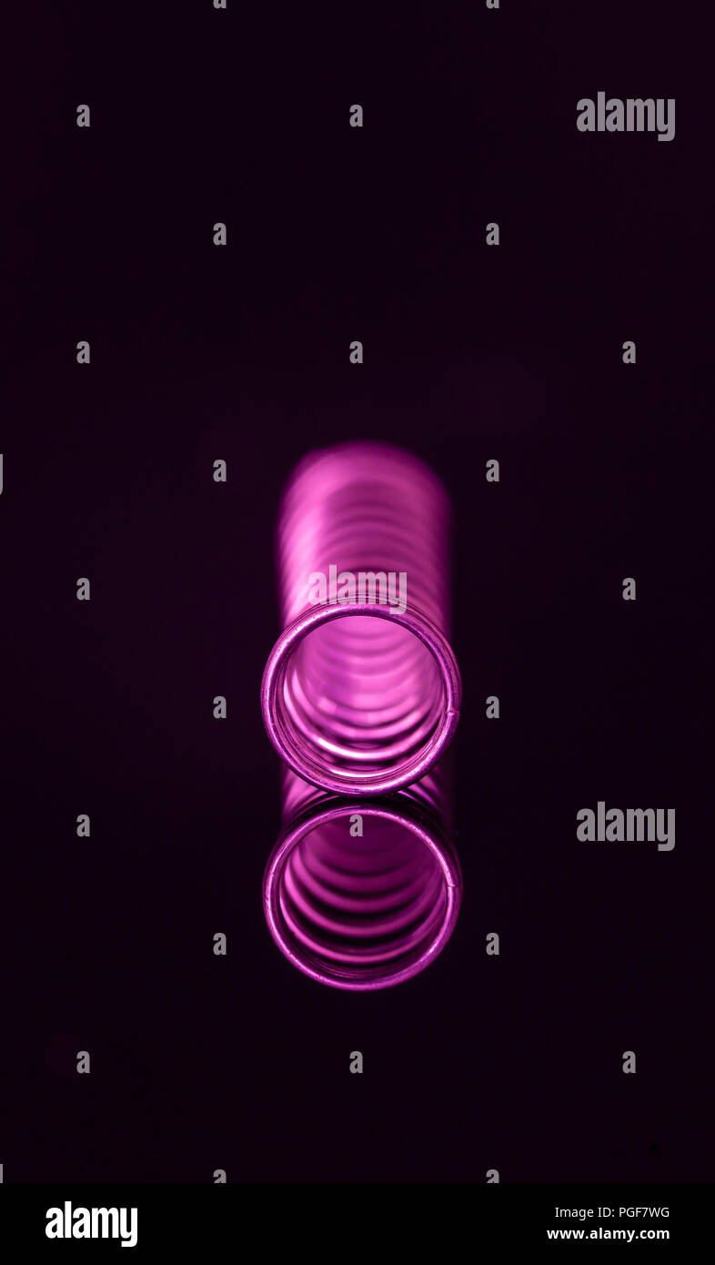 Pink metal spring isolated on black background with reflection. Macro ...