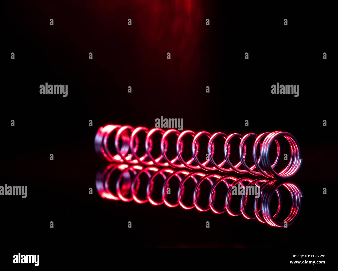 Red metal spring isolated on black background with reflection. Macro ...