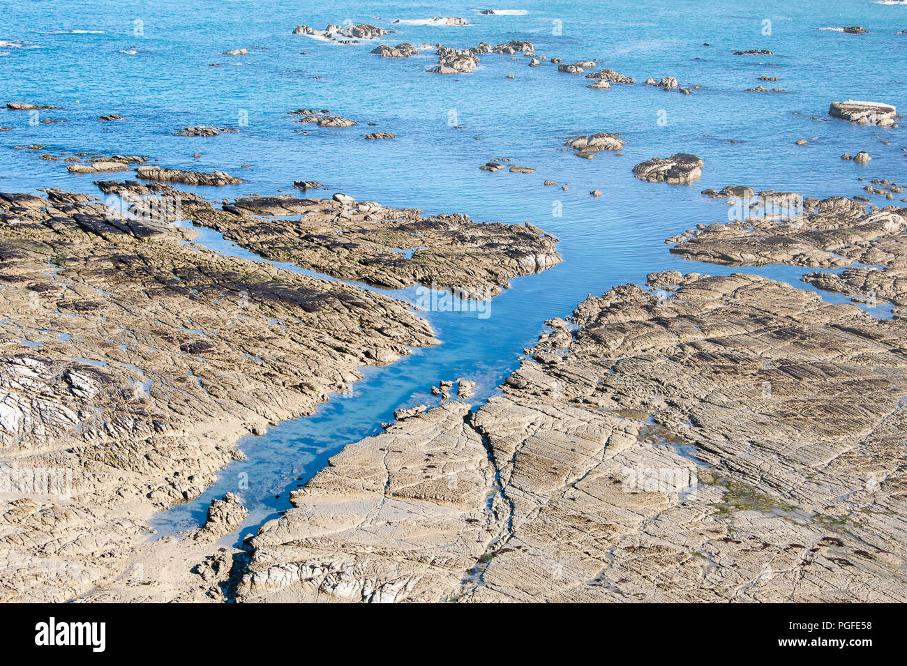 Aerial view to exposed rocks along shoreline. Turquoise sea contrasts ...