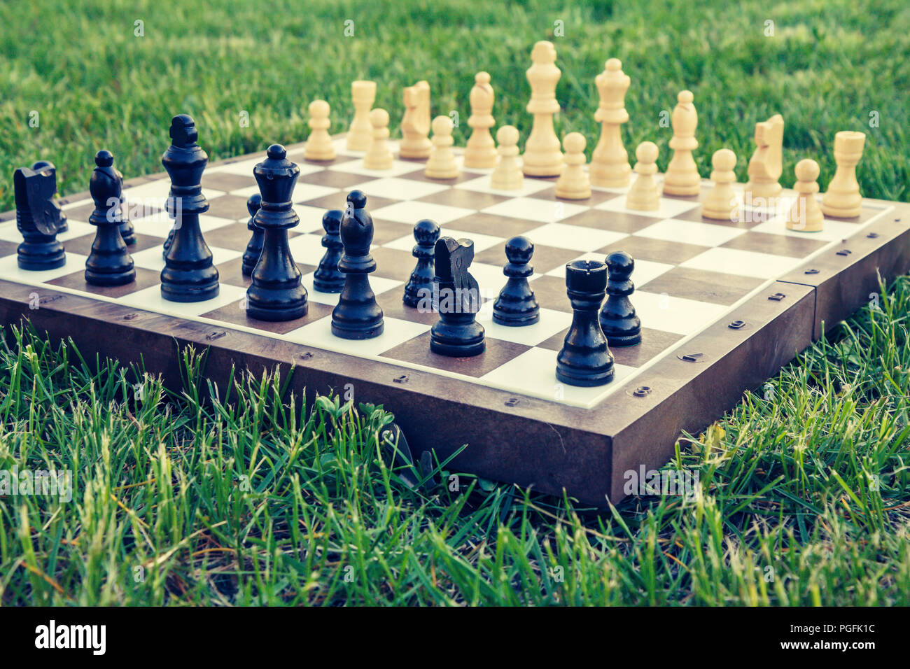 Chess board with chess pieces on green grass in daylight. Selective ...