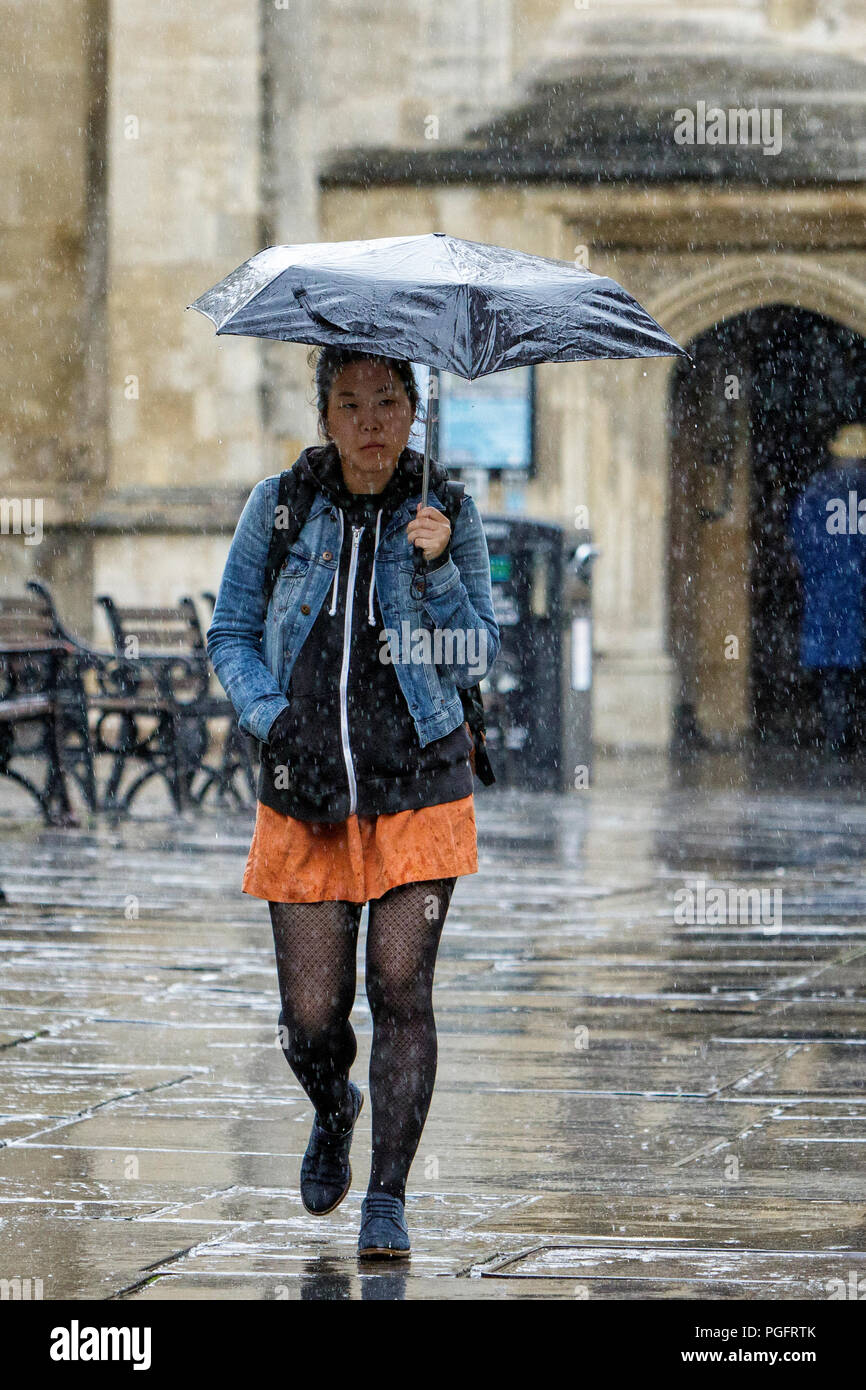 Bath, UK, 26th August, 2018. A woman is pictured braving heavy rain in ...