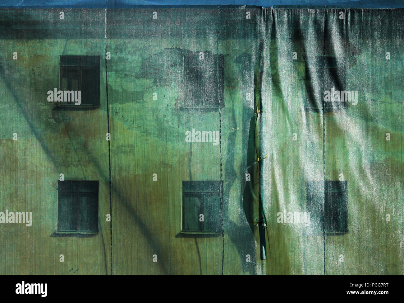 The green building mesh on old house with windows protects the old ...