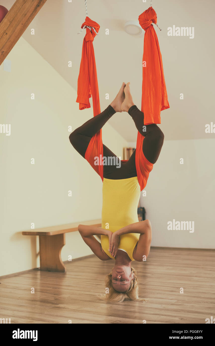Woman doing aerial yoga in the fitness studio.Image is intentionally ...