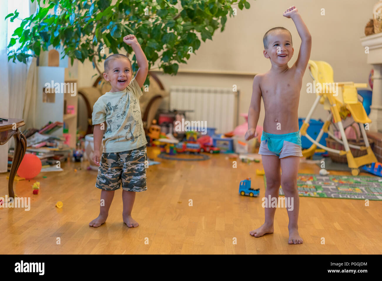 Two little boys are doing exercises. Two small boys at home doing ...