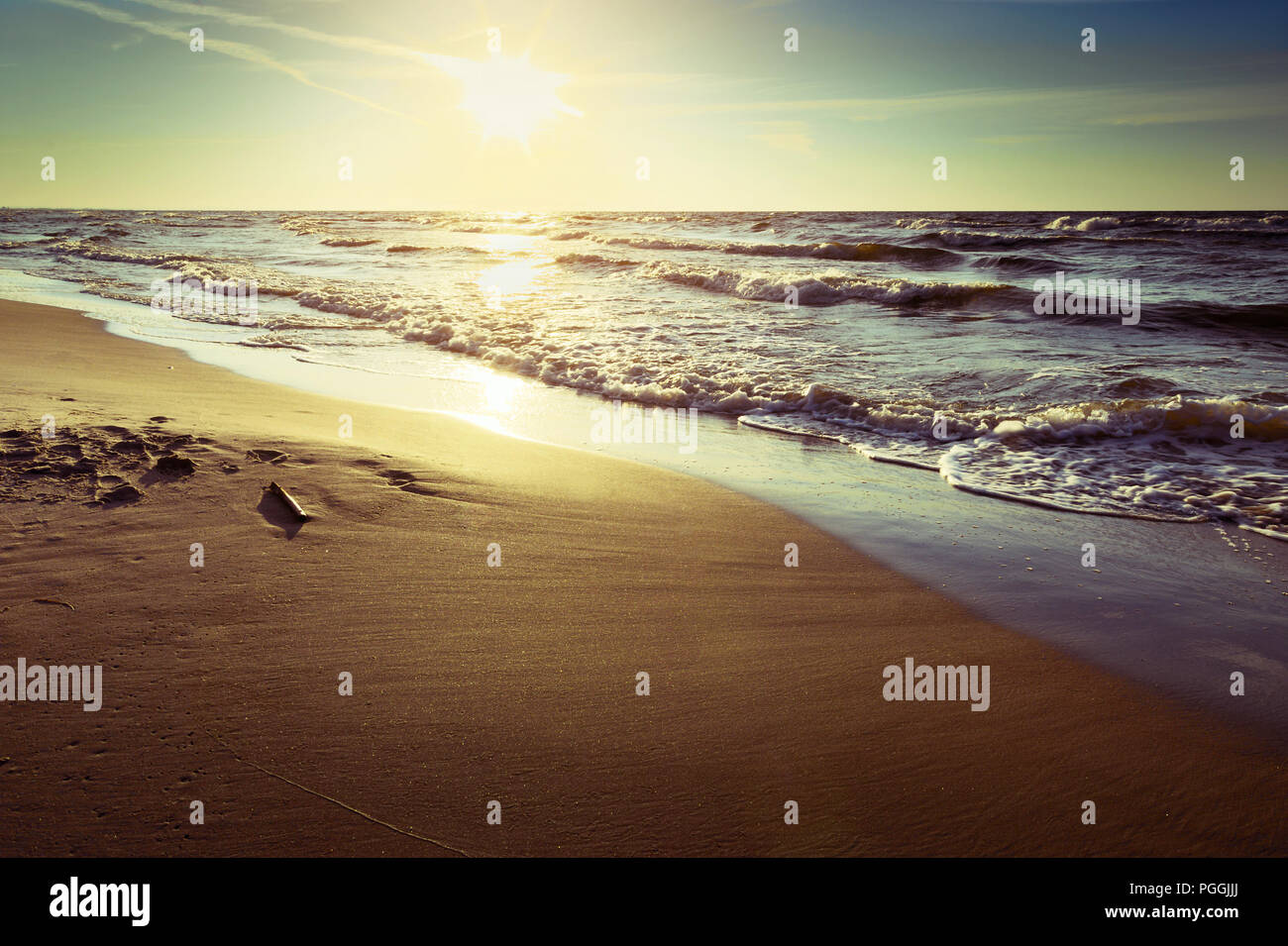 Baltic sea coast with waves breaking on the beach at sunset. Scenic picturesque summer seascape ...