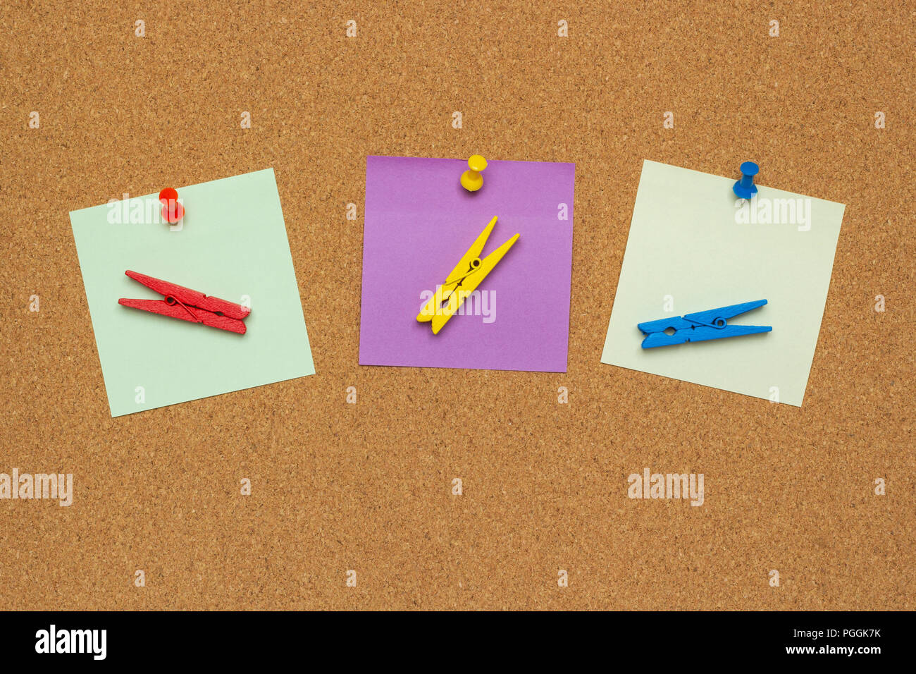 Three colorful notes with pushpins and clothespins isolated on a cork ...