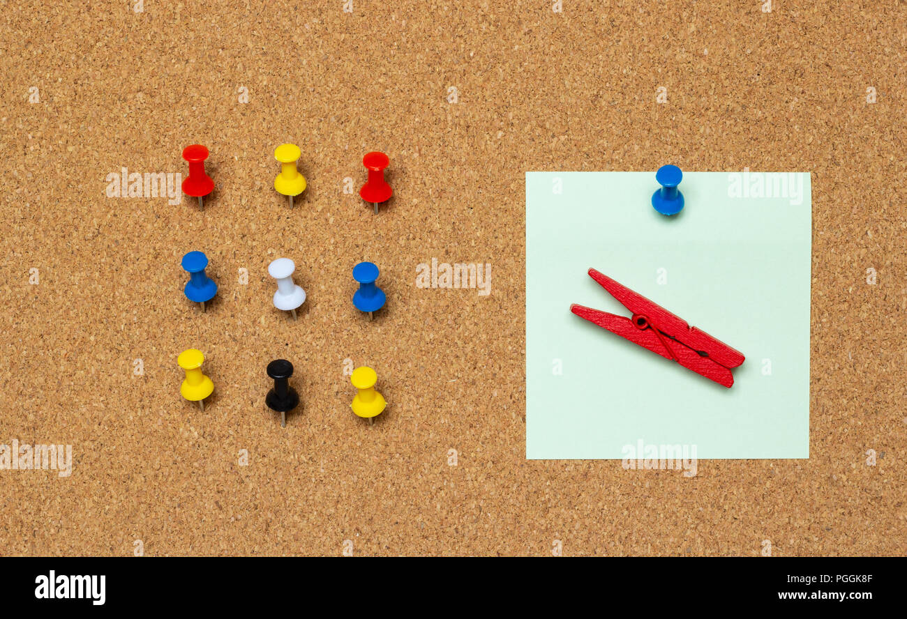 Nine color buttons and a sticker with a clothespin on a cork board ...