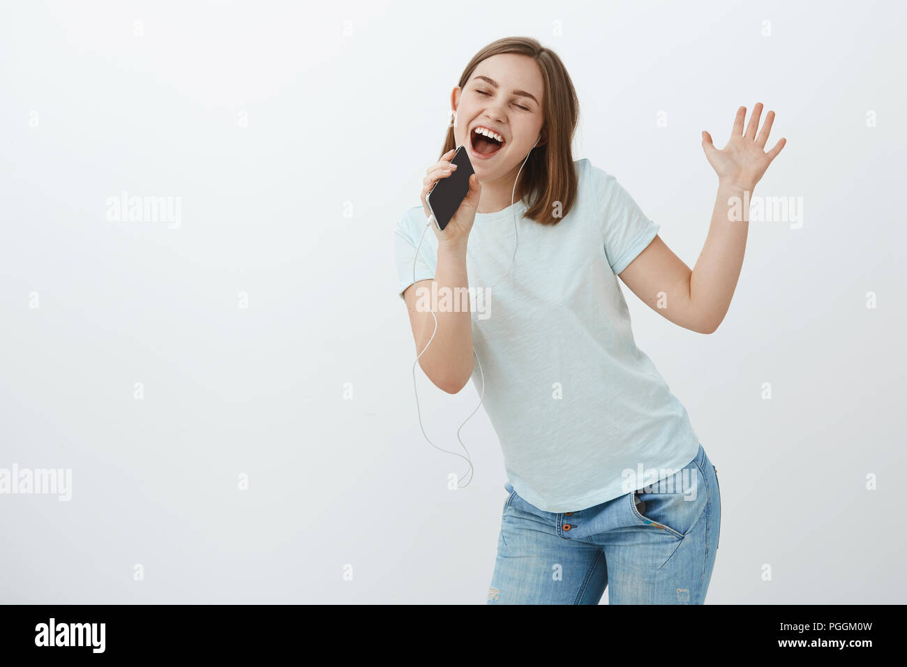 Feeling like popular singer on stage. Amused and energized female in t ...