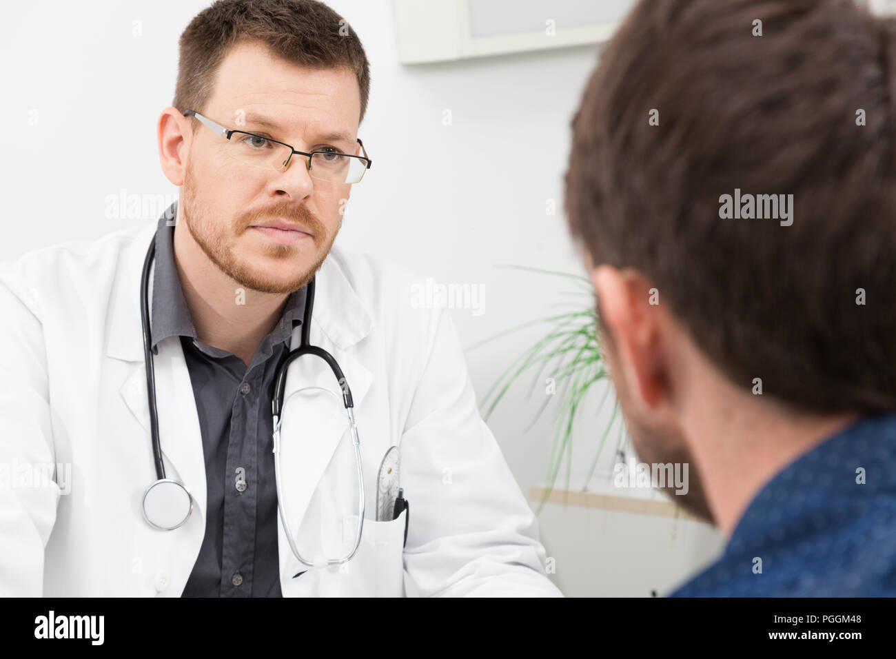 A doctor listens to his patient in a medical practice with a ...