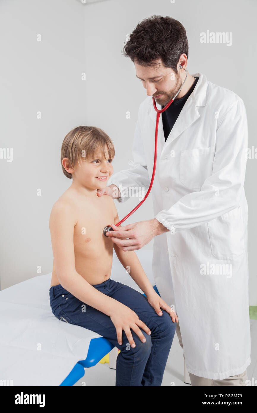 A children doctor with stethoscope auscultating the chest of a smiling ...