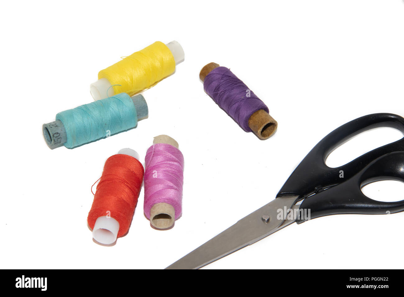 colored thread and scissors on a white background. items for embroidery ...