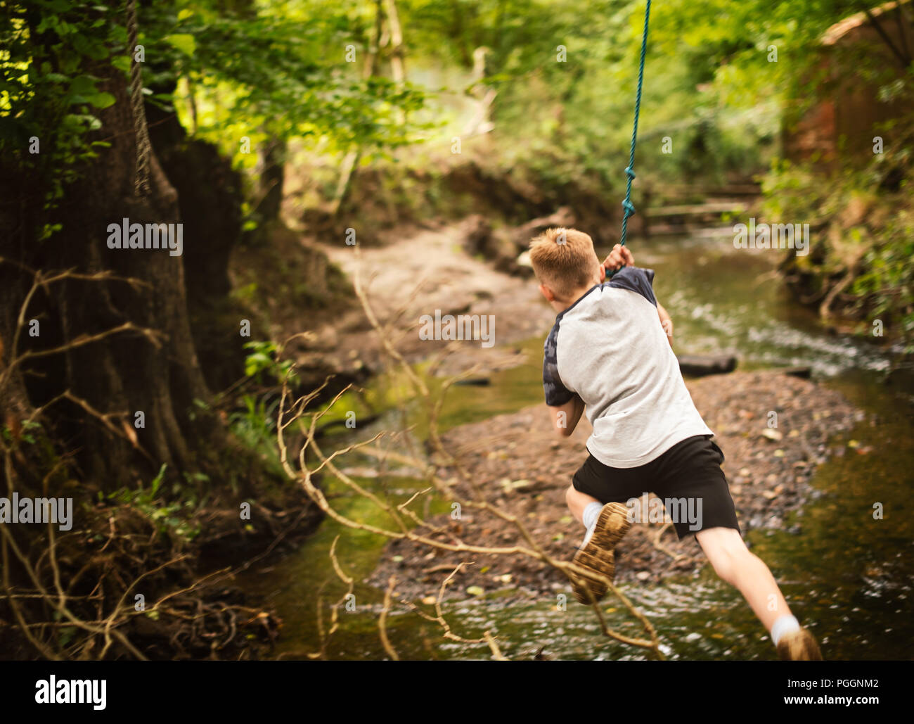 Boy swinging on rope swing Stock Photo - Alamy