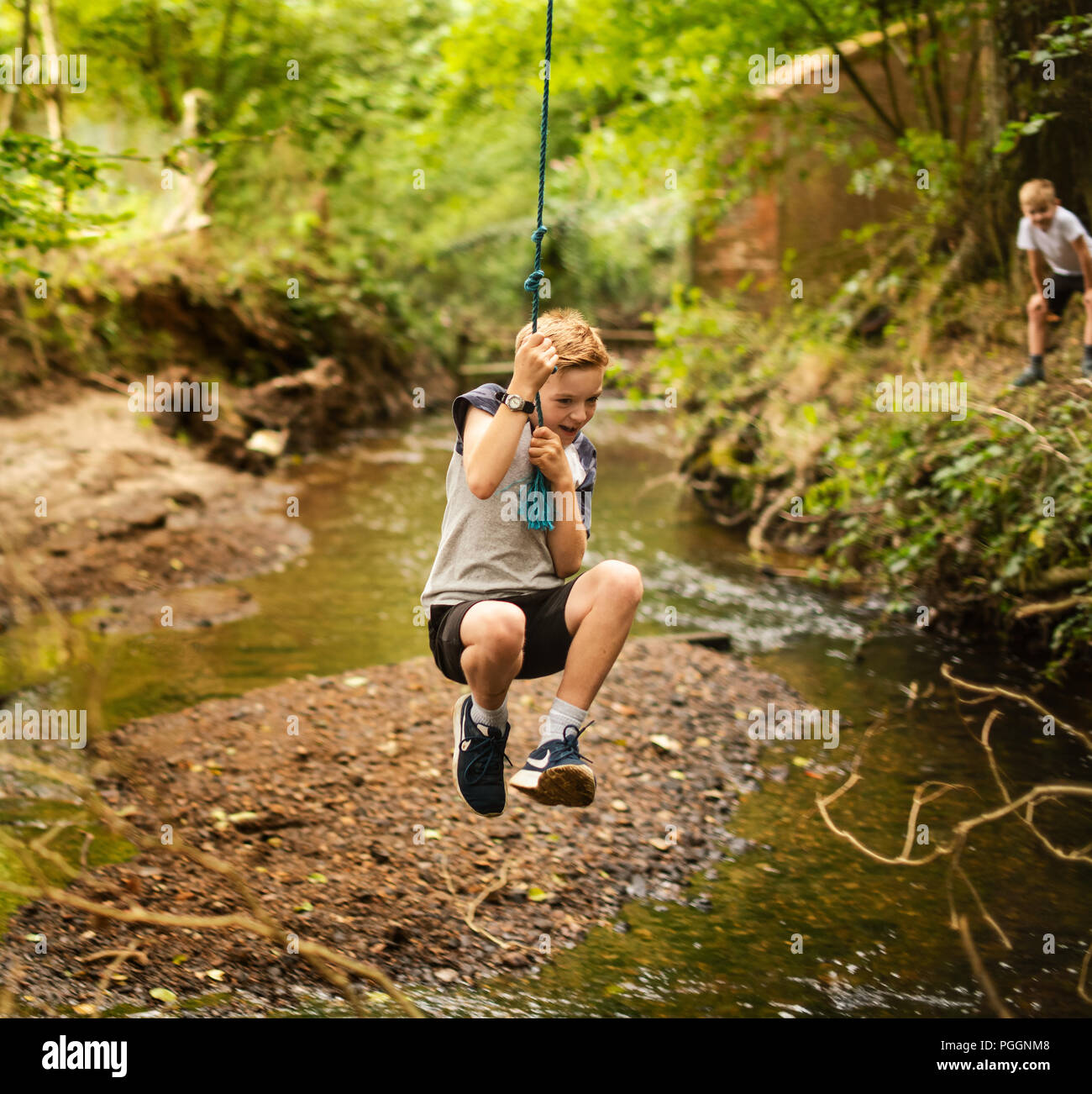 Boy swinging on rope swing Stock Photo - Alamy