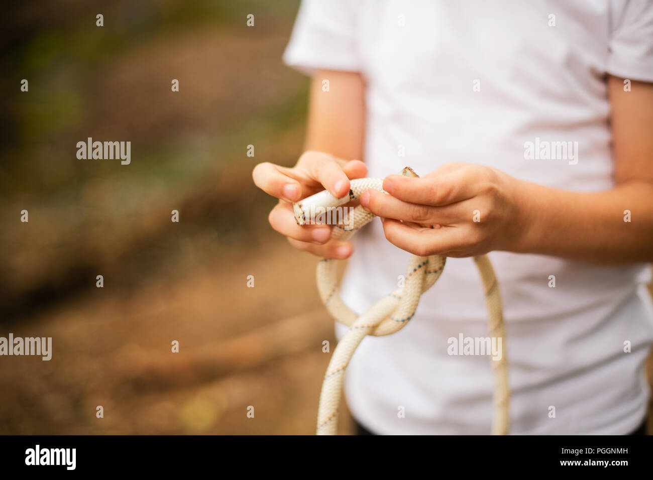 Boy tying knot in rope Stock Photo - Alamy