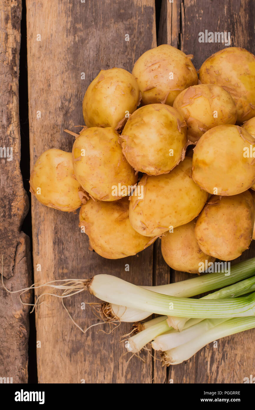 Pile of potatoes and green onions. Old rustic wooden desk background ...