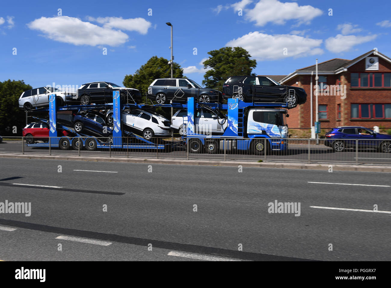 A car transporter drives along a dual carriageway fully laden with ...