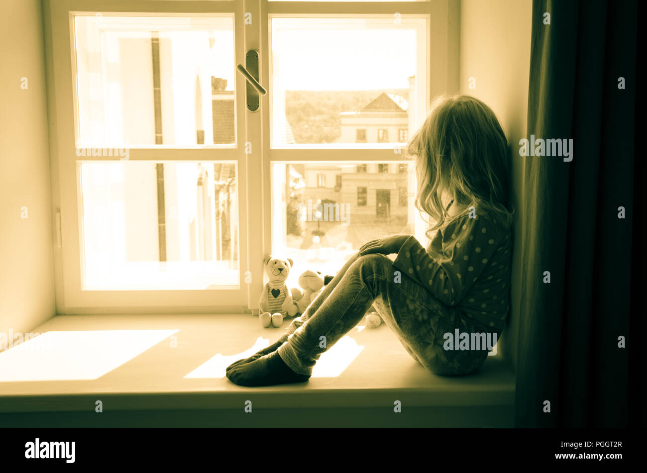 little blond girl sitting and looking over window Stock Photo - Alamy