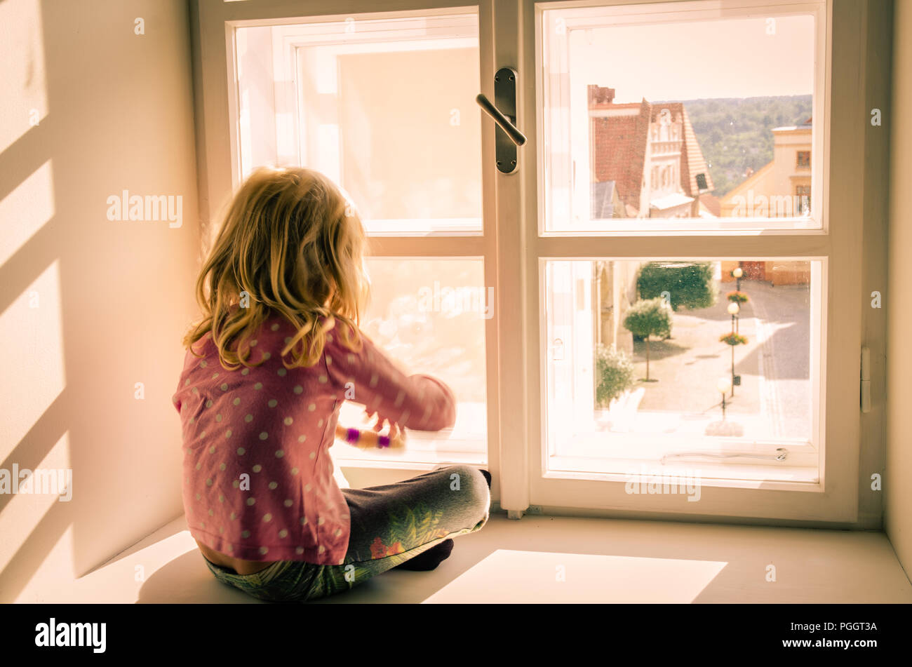 little blond girl sitting and looking over window Stock Photo - Alamy