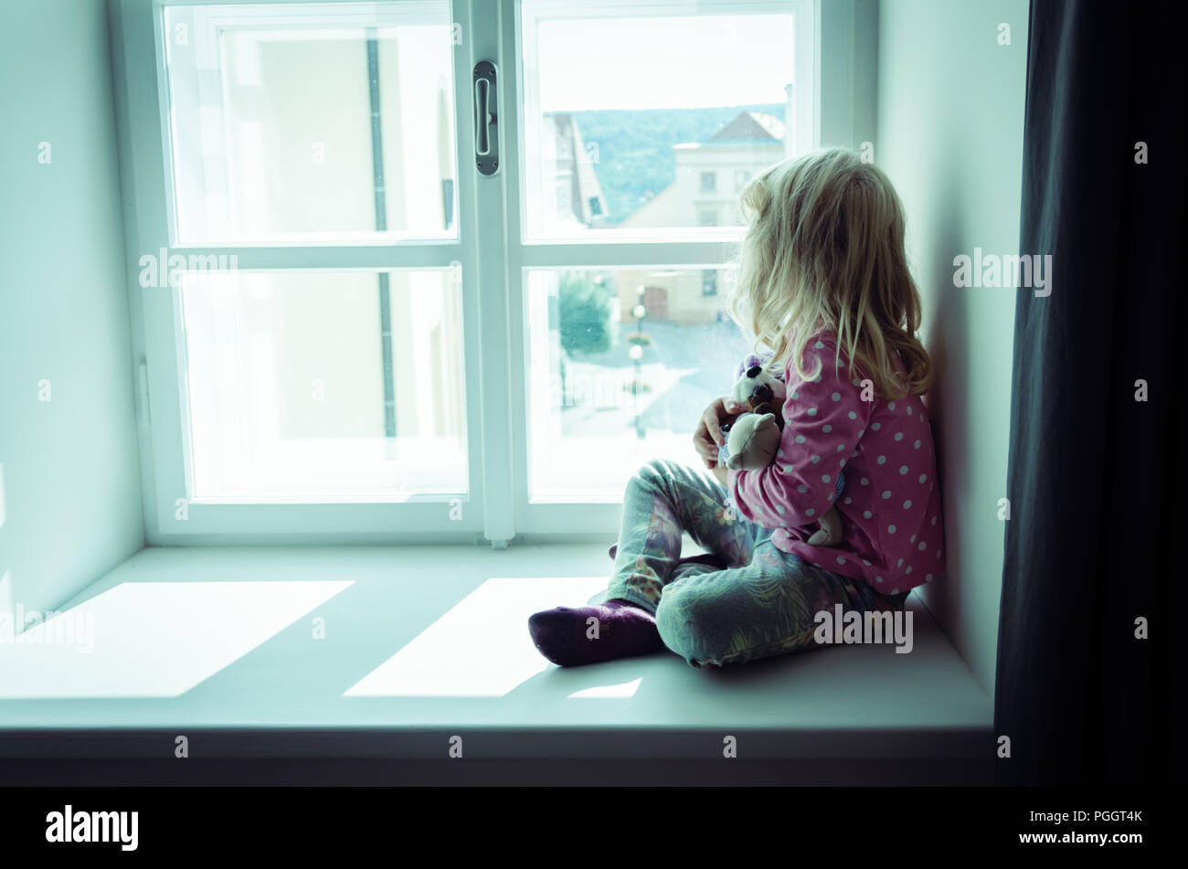 little blond girl sitting and looking over window Stock Photo - Alamy