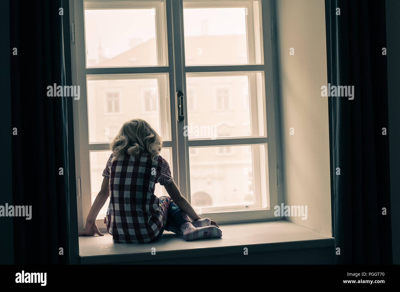 little blond girl sitting and looking over window Stock Photo - Alamy