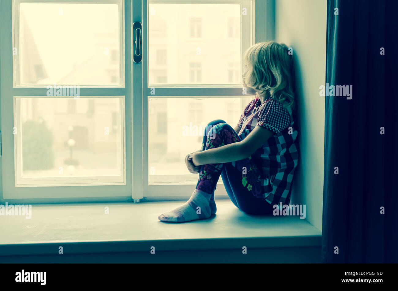 little blond girl sitting and looking over window Stock Photo - Alamy