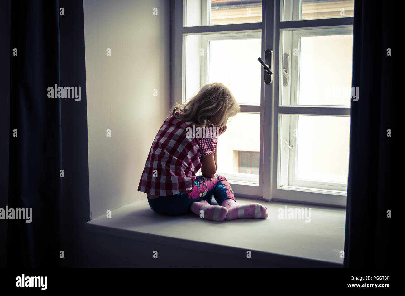 little blond girl sitting and looking over window Stock Photo - Alamy