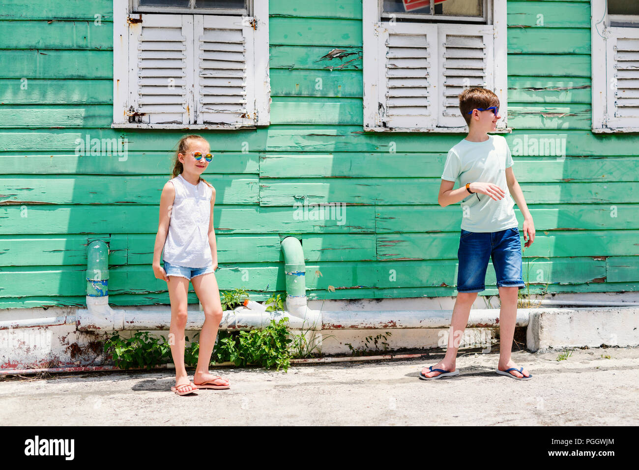 Two kids boy and girl outdoors against colorful house on Barbados ...