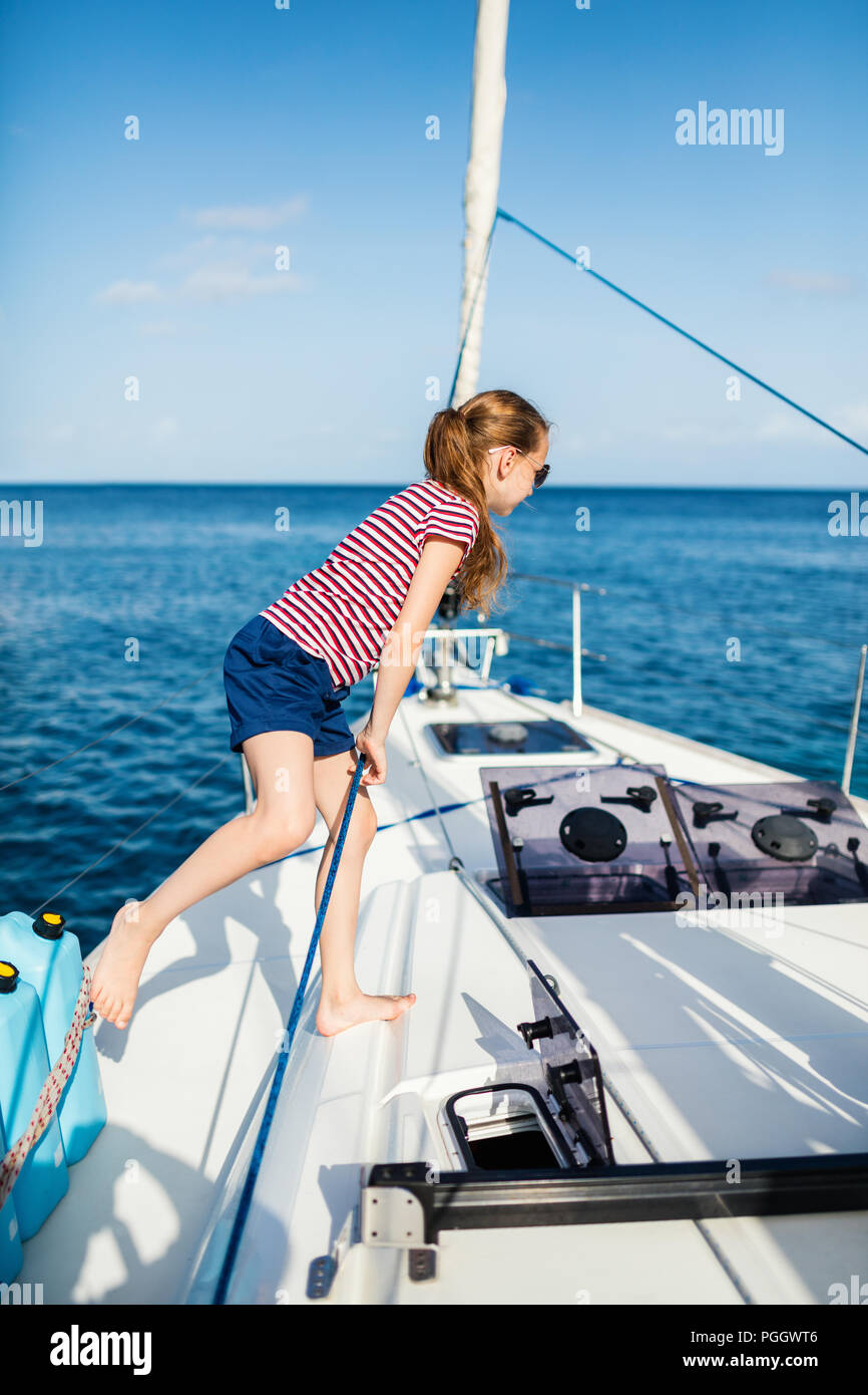 Adorable little girl enjoying sailing on a luxury catamaran or yacht ...