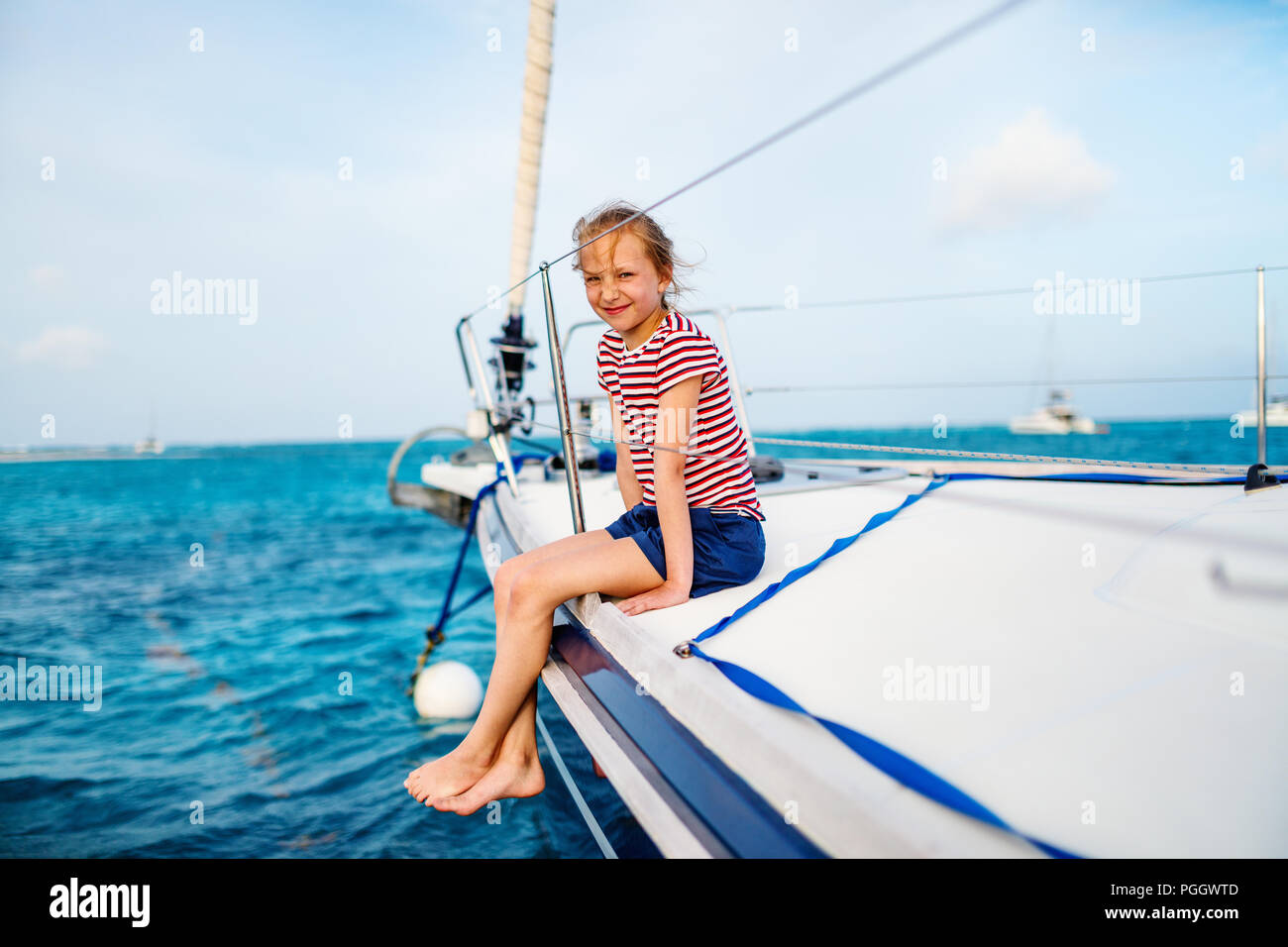 Adorable little girl enjoying sailing on a luxury catamaran or yacht ...