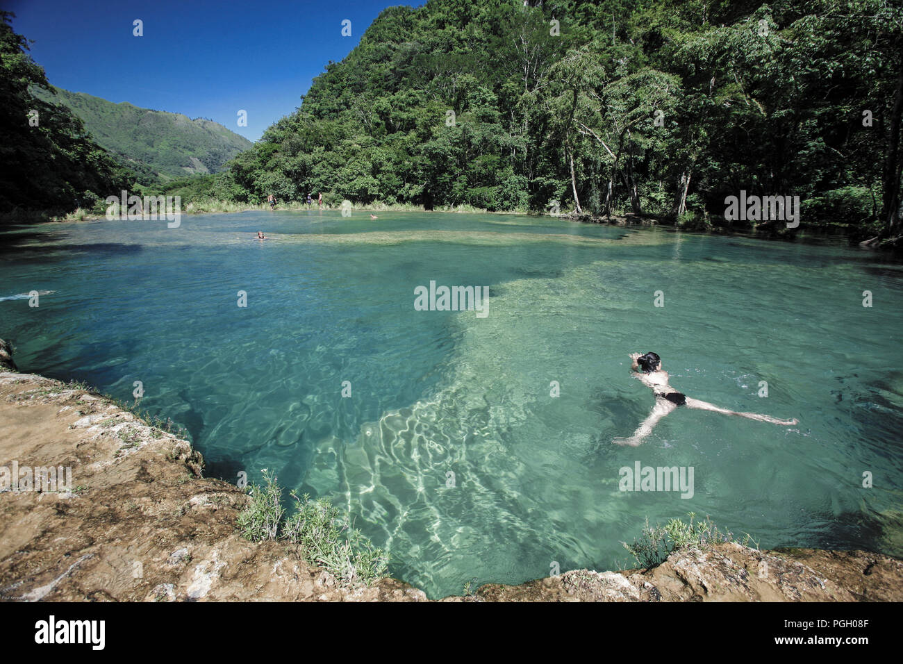 Female swimming in the cool water turquoise pools of Semuc Champey ...