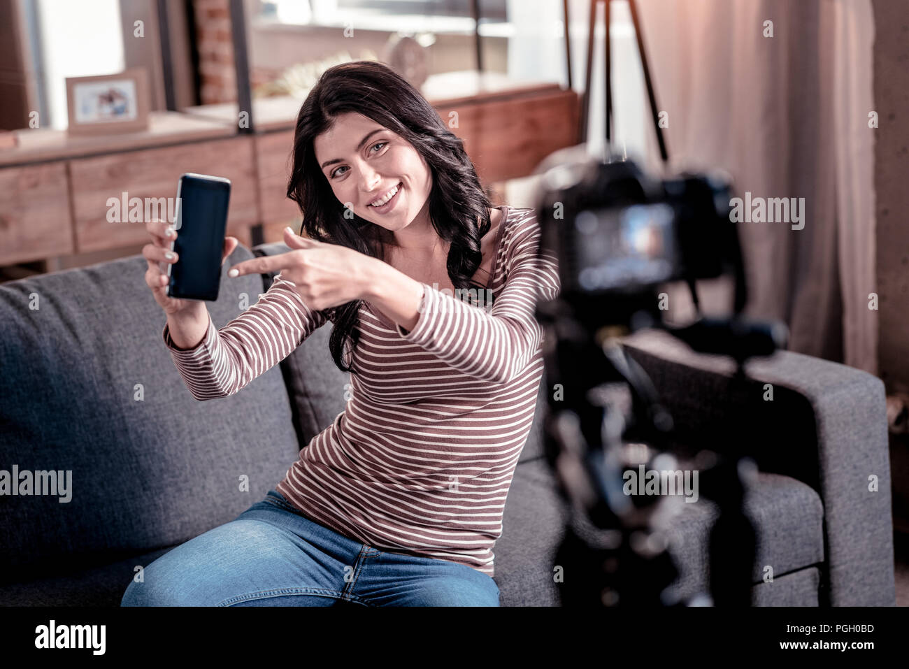 Happy female vlogger holding her phone Stock Photo - Alamy