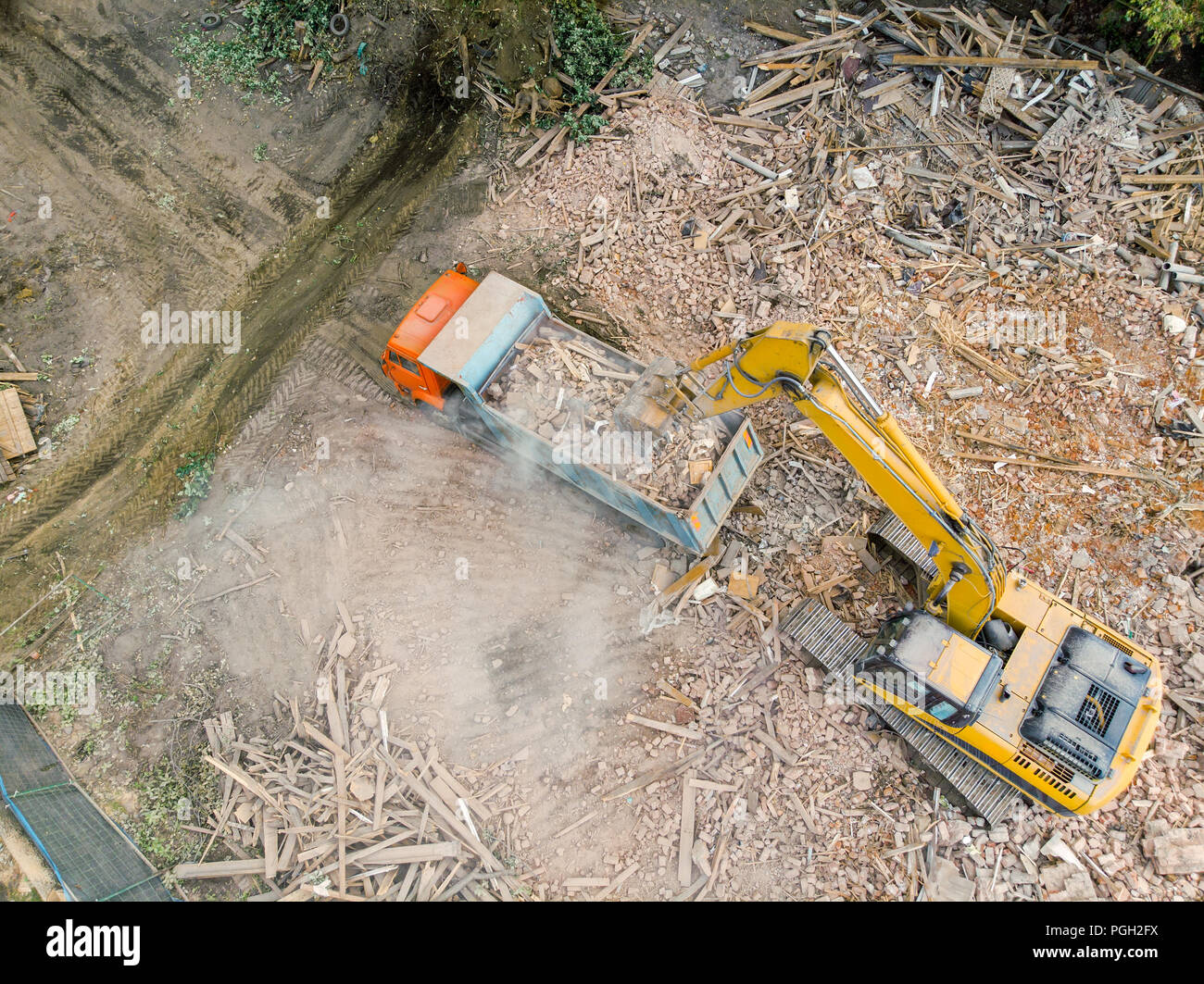 excavator loading dumper truck with debris of destroyed building. aerial photo Stock Photo - Alamy