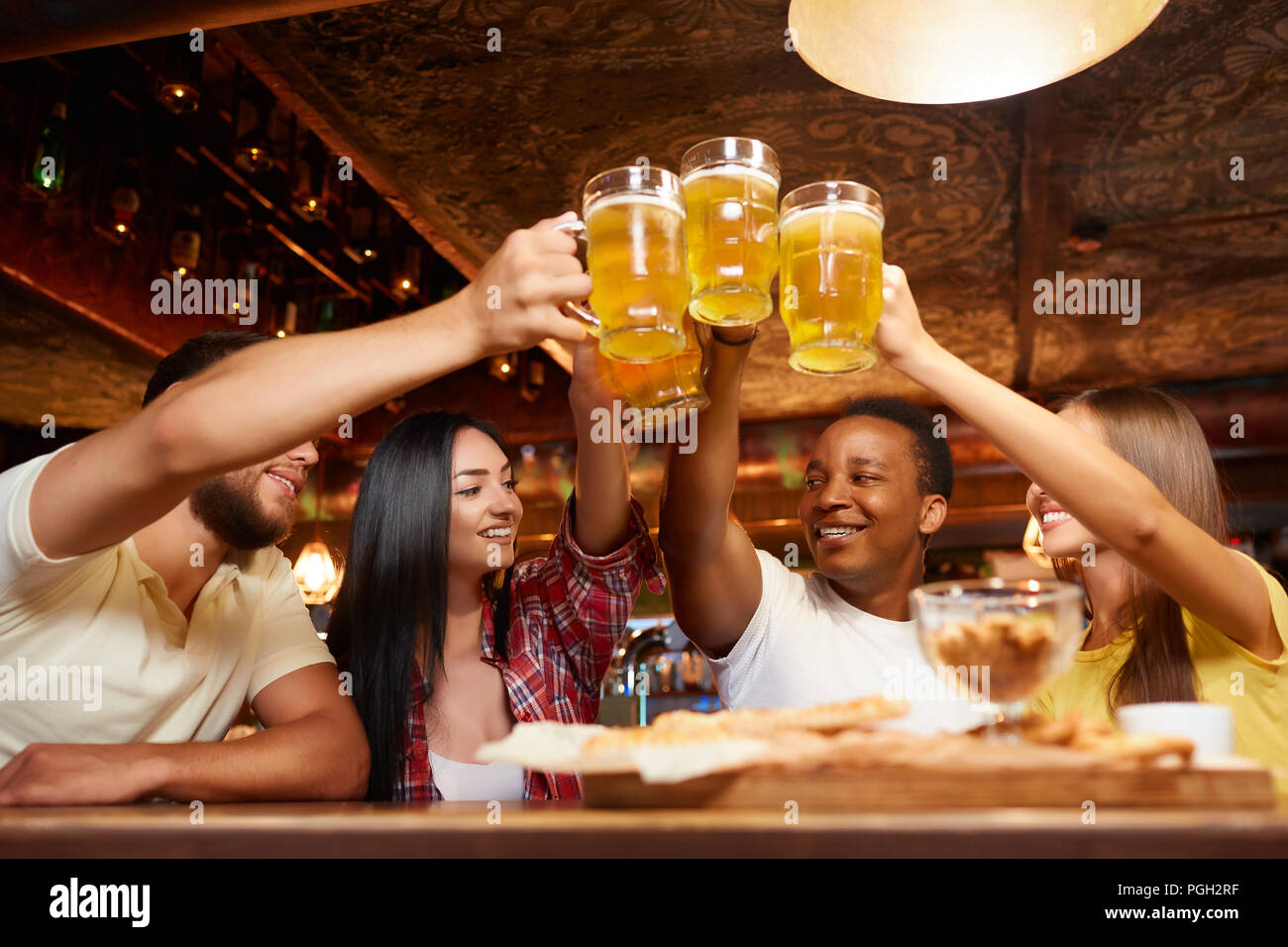 Four boys and two girls having fun together, raising beer clinking ...