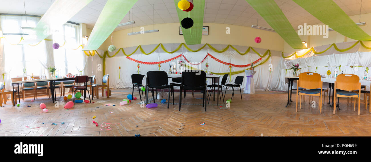 An abandoned hall at the end of a party. Colourful balloons lie on the ...