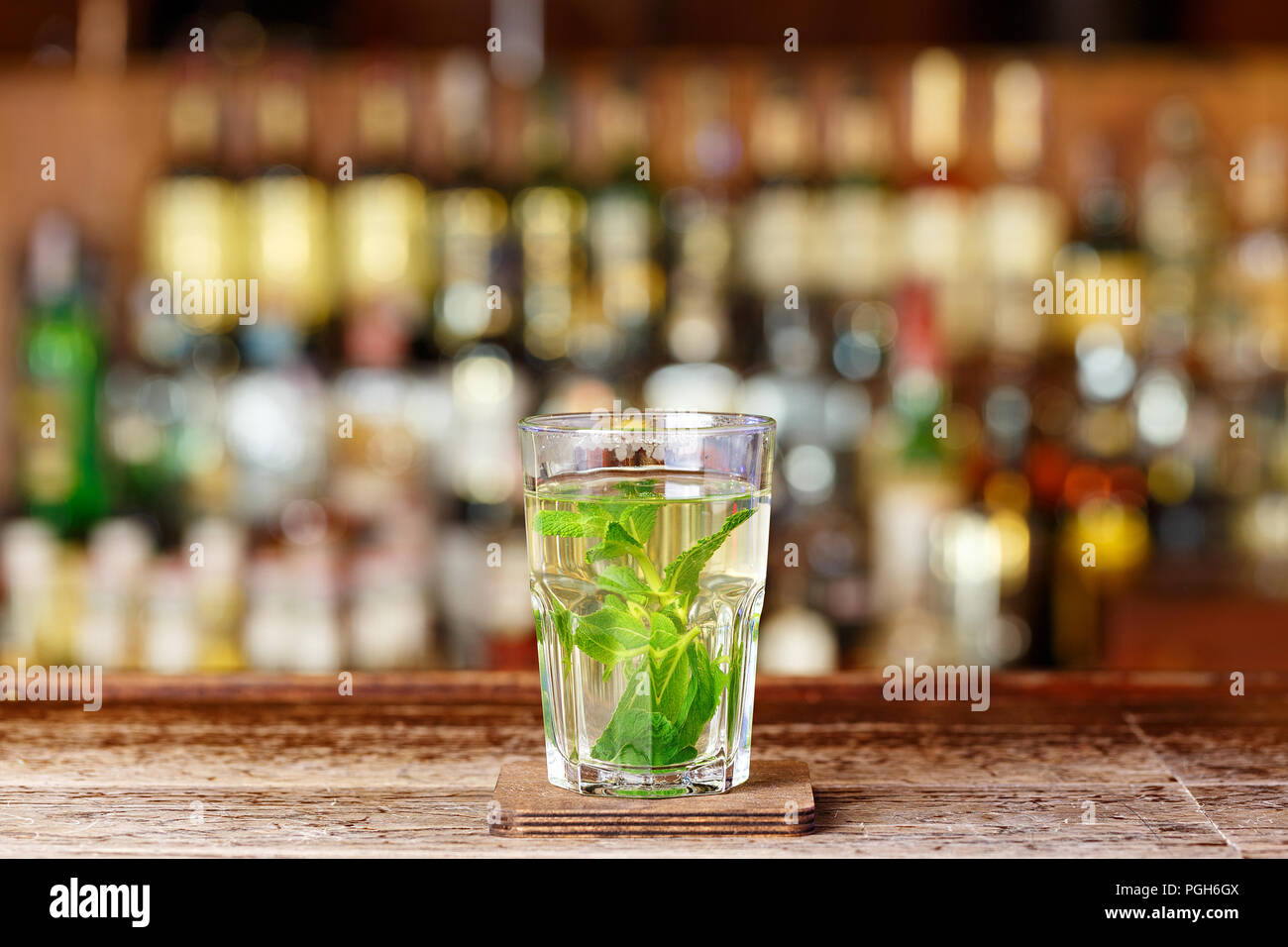 An invigorating gin-based cocktail is on the bar counter on a blurry ...