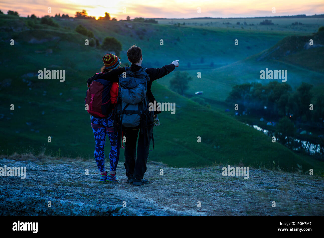 Photo from back of hugging man and tourist woman with backpacks on ...