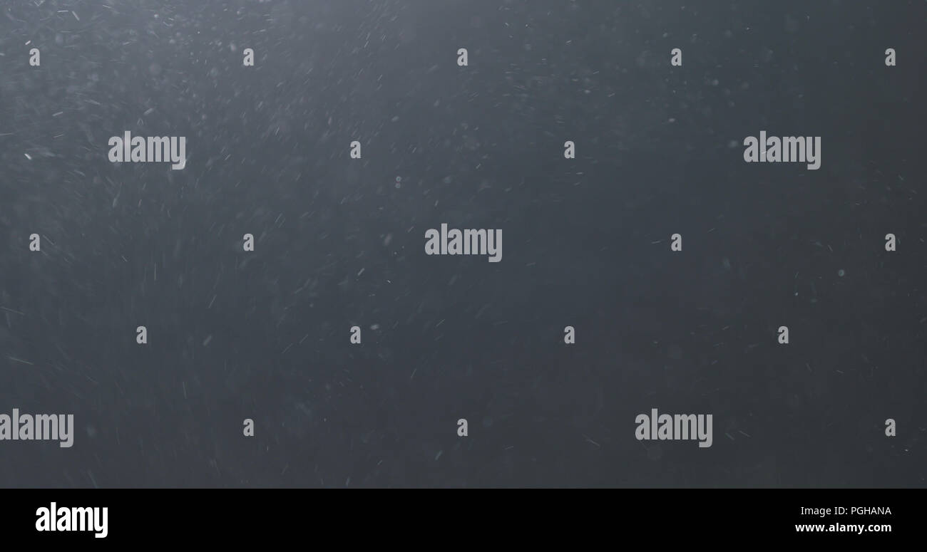 Macro shot of fast moving dust particles on a black background, wide ...