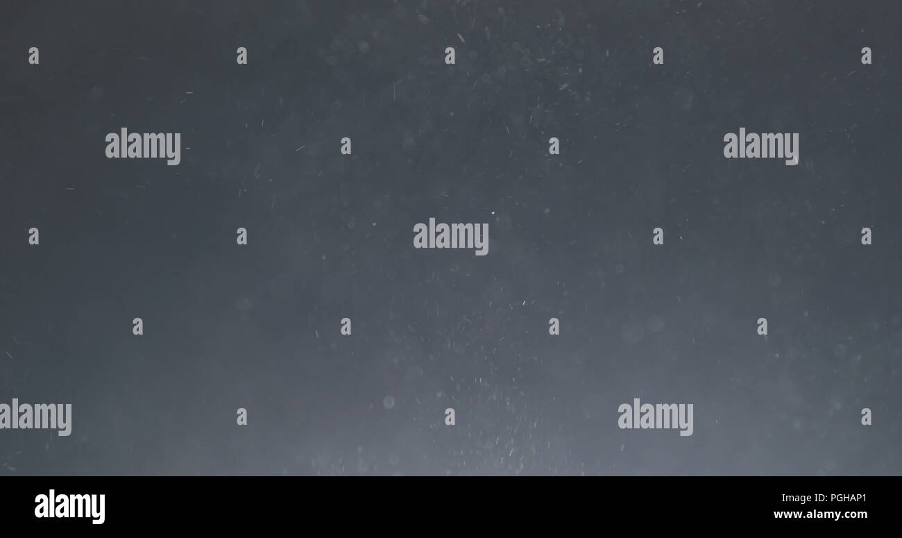 Macro shot of fast moving dust particles on a black background, wide ...