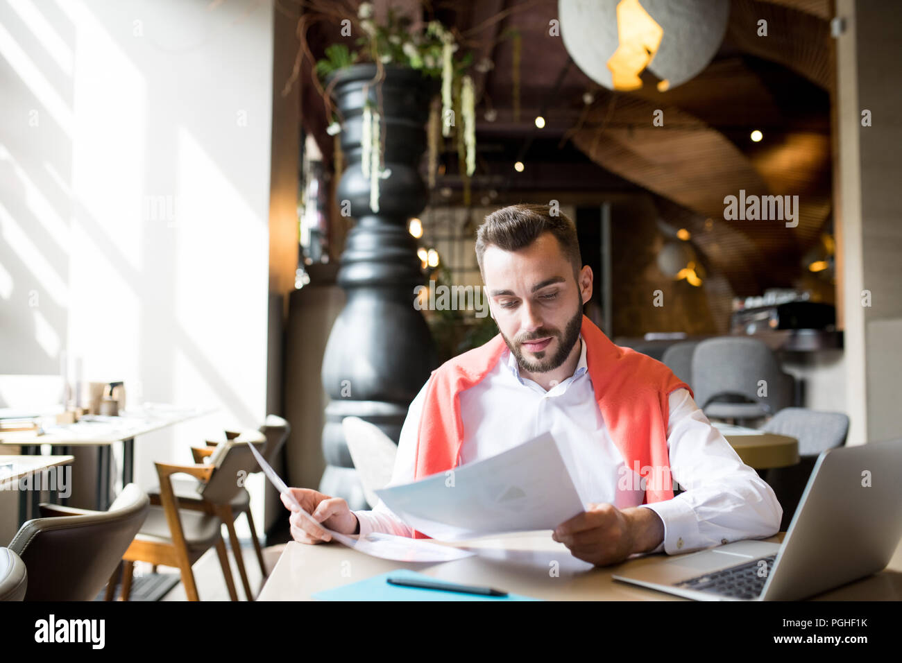 Portrait of handsome entrepreneur reading documents while working in ...