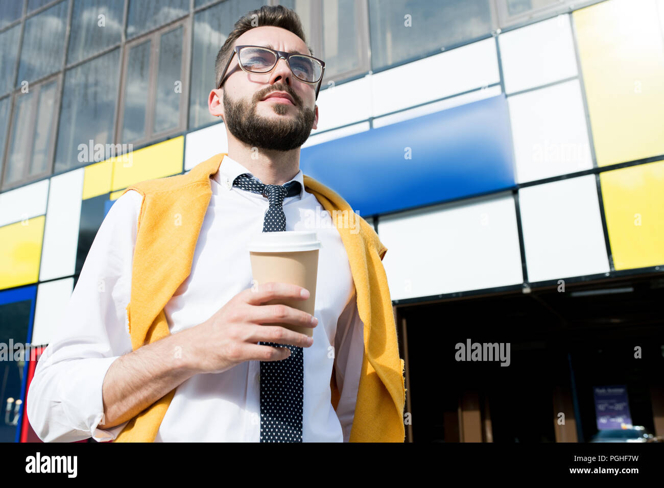 Low angle portrait of contemporary entrepreneur drinking coffee ...