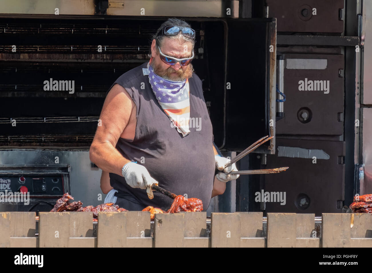 Experienced pit master sauces ribs and chicken on the BBQ at the annual ...
