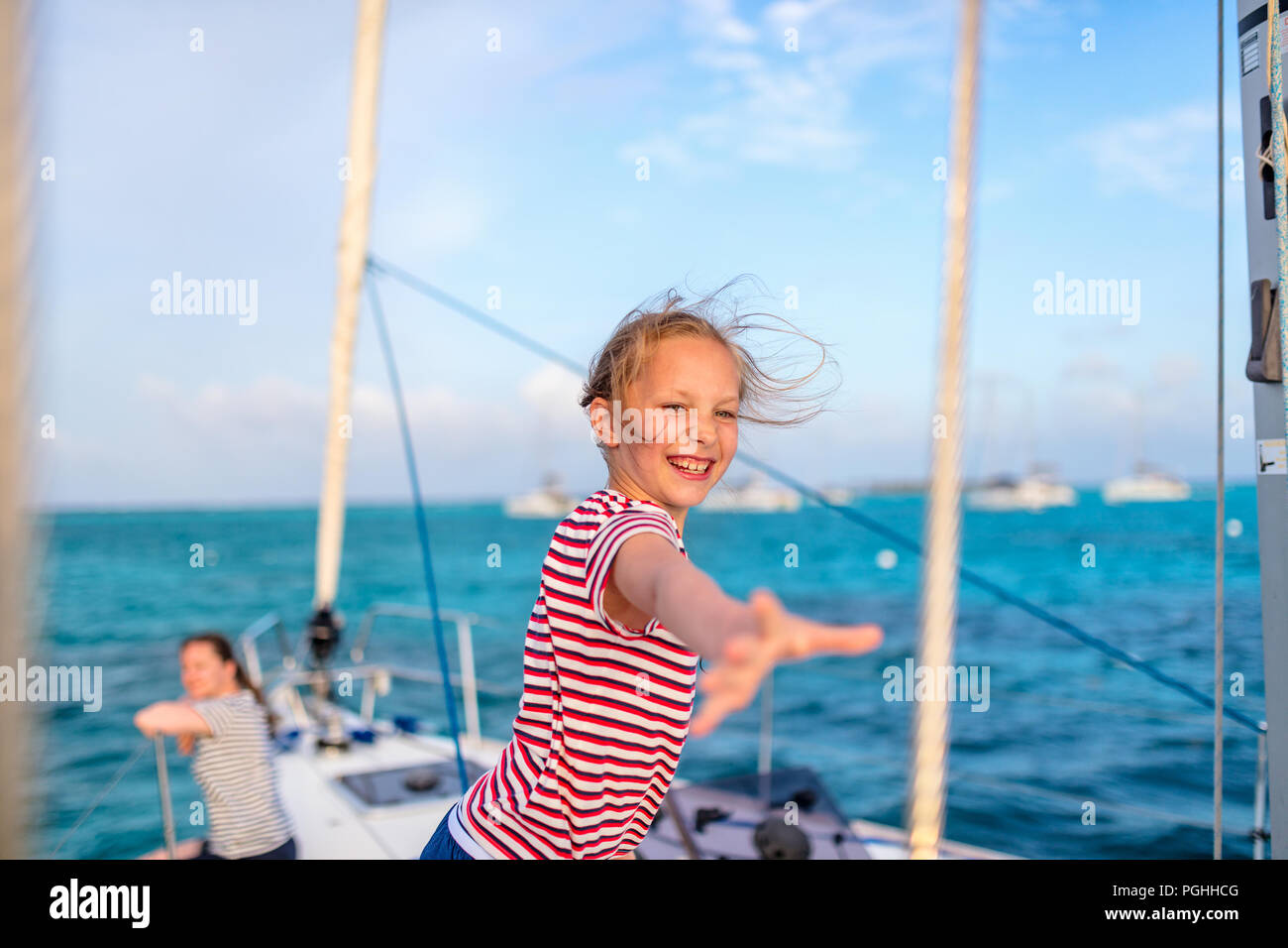 Adorable little girl enjoying sailing on a luxury catamaran or yacht ...